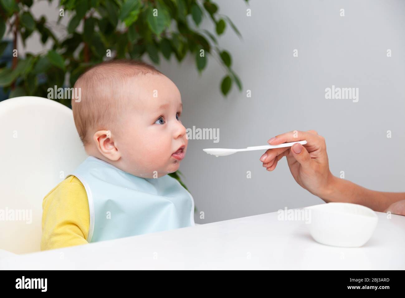 Little baby boy in color clothes eating yoghurt from spoon, dirty mouth ...