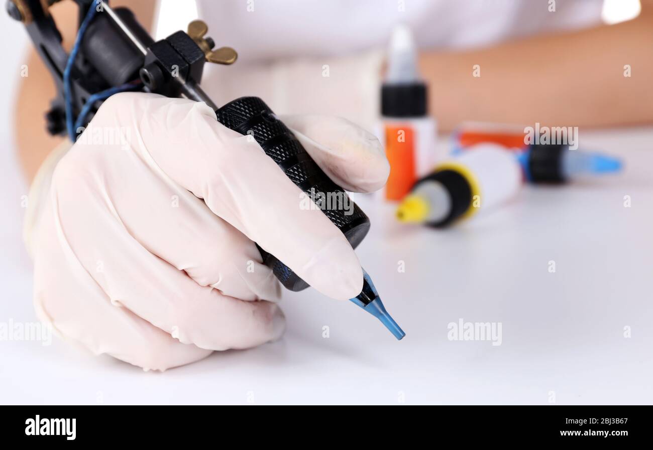 Tattoo machine in hand and colourful ink on white background Stock ...