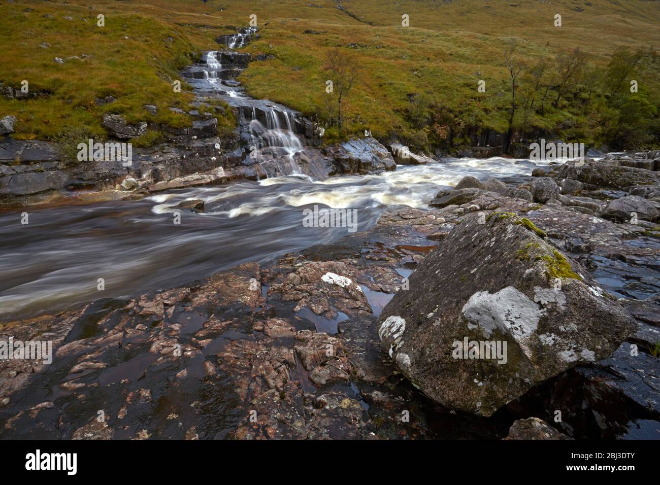 A tributary stream flows into the River Etive in Glen Etive Stock Photo ...