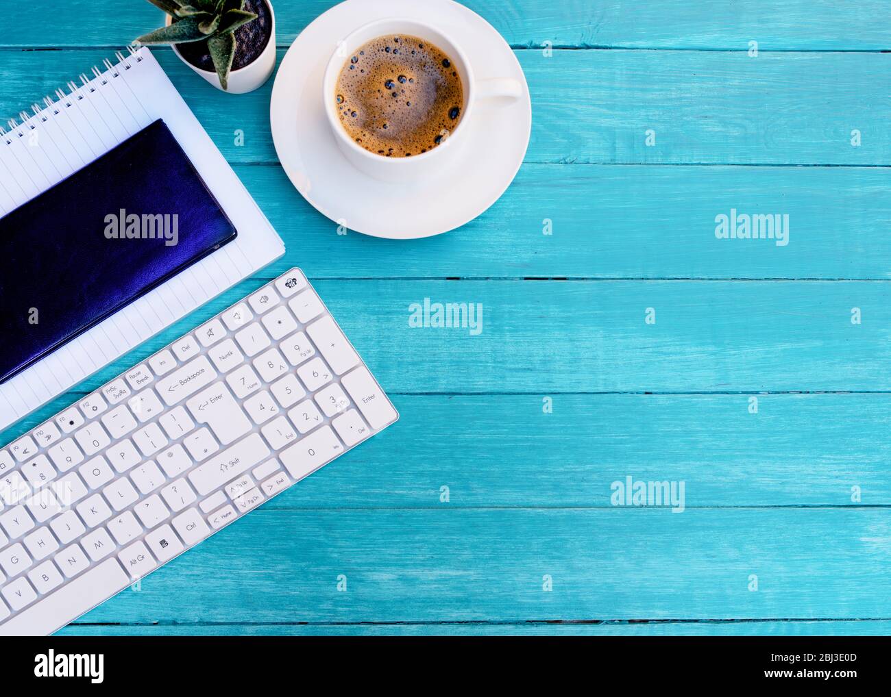 Mockup of white Keyboard, a cup of coffee, cactus on turquoise wood ...