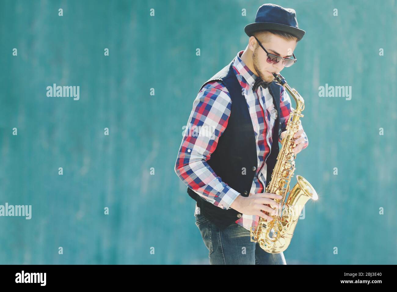 Young man playing on saxophone outside near the old wall Stock Photo ...