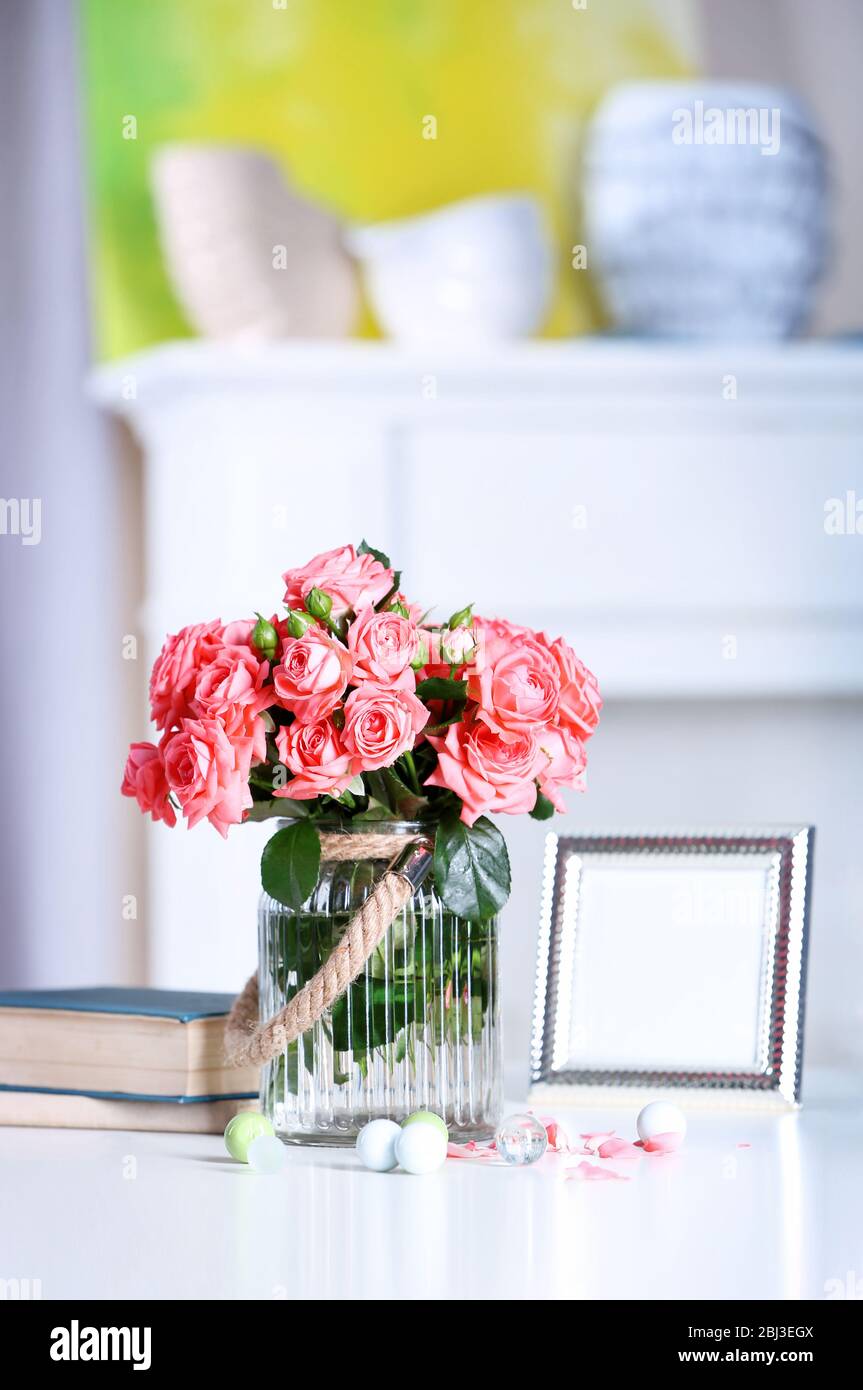 Beautiful rose in vase on table in room Stock Photo - Alamy