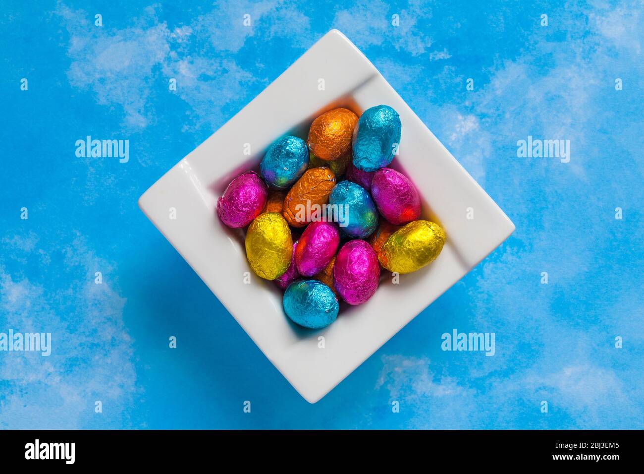 solid milk chocolate mini Easter eggs foil wrapped in bowl on blue ...