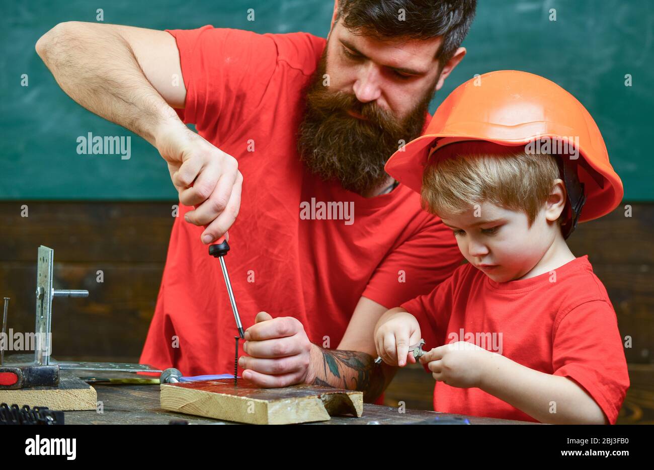 Father, parent with beard teaching little son to use tool screwdriver ...