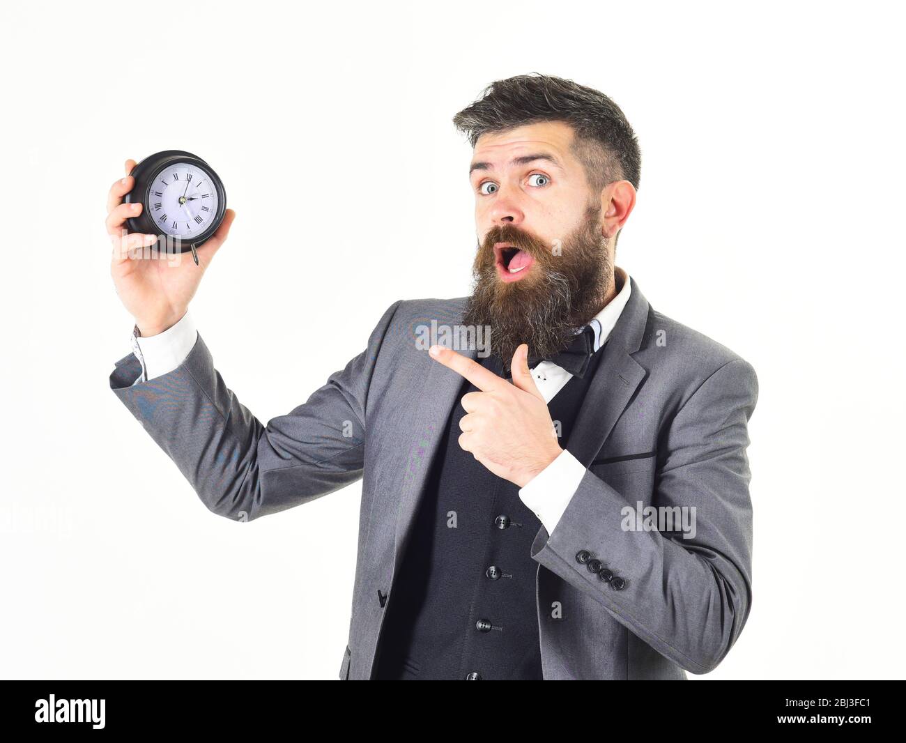 Bearded man holds alarm clock. Guy points finger on alarm clock Stock ...