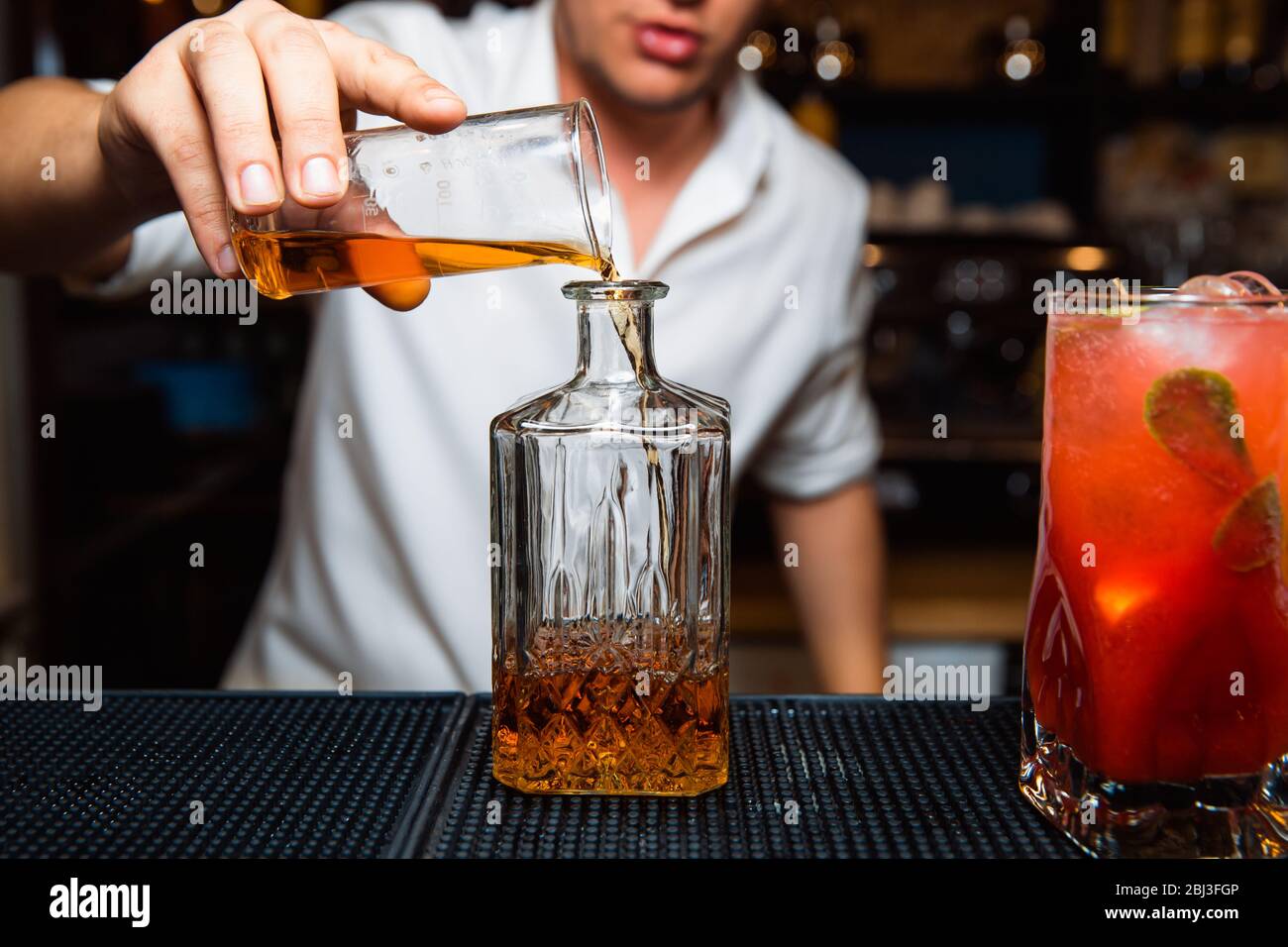 The barman pours whiskey into a transparent decanter Stock Photo - Alamy