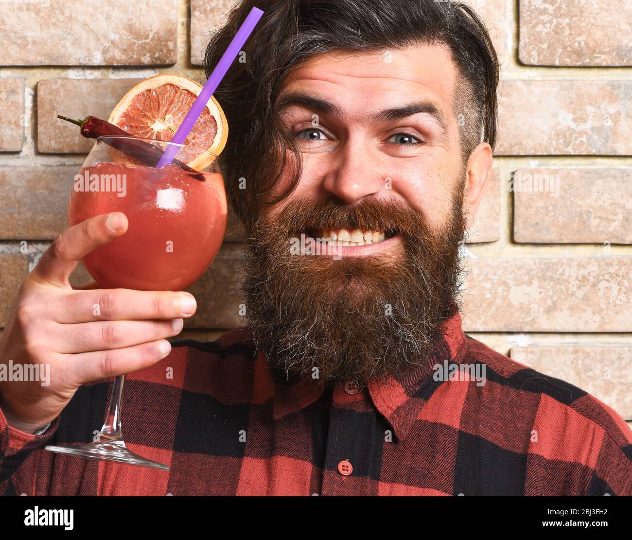 Barman with beard and cheerful face holds glass with cocktail. Hipster ...