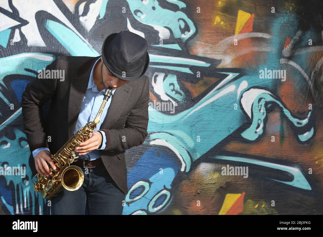 Saxophone player on graffiti wall background Stock Photo - Alamy