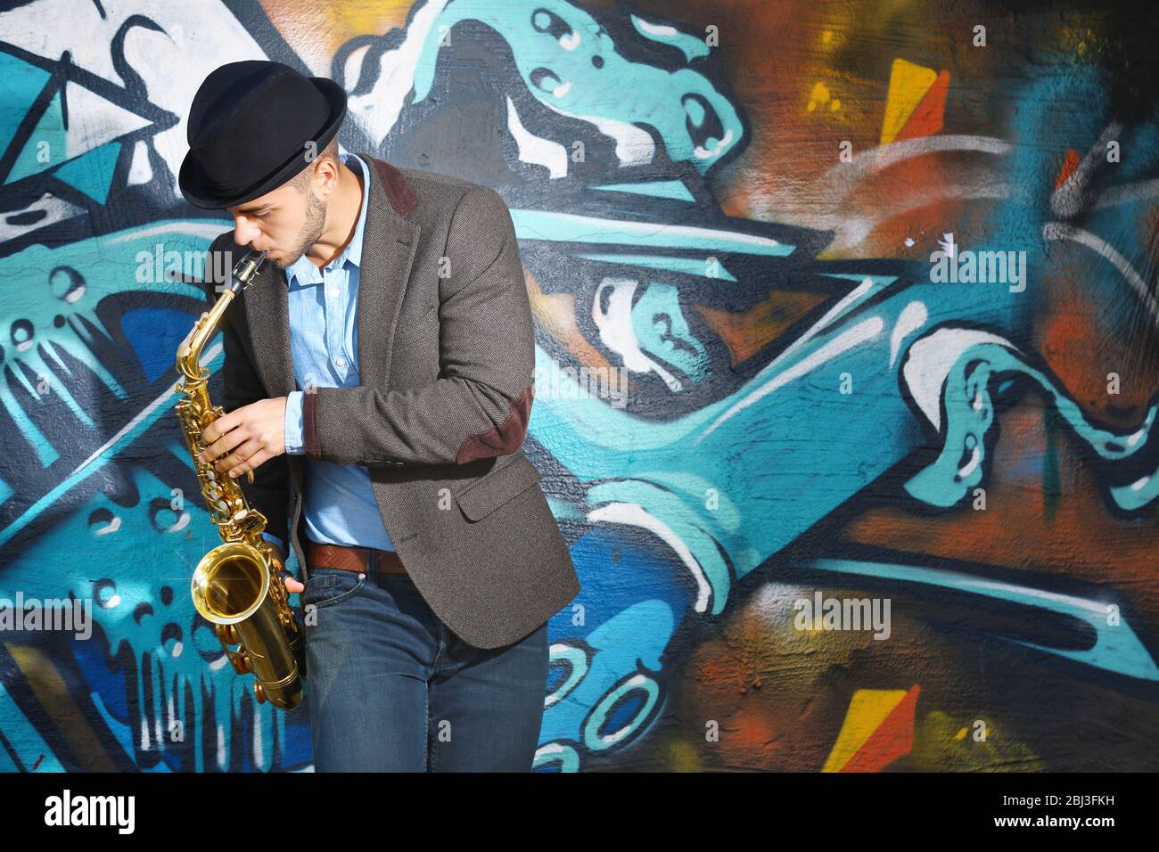 Saxophone player on graffiti wall background Stock Photo - Alamy
