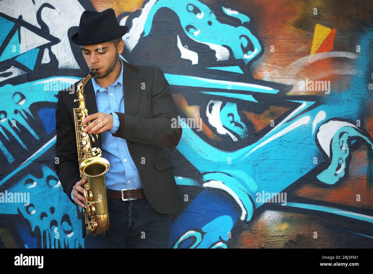 Saxophone player on graffiti wall background Stock Photo - Alamy