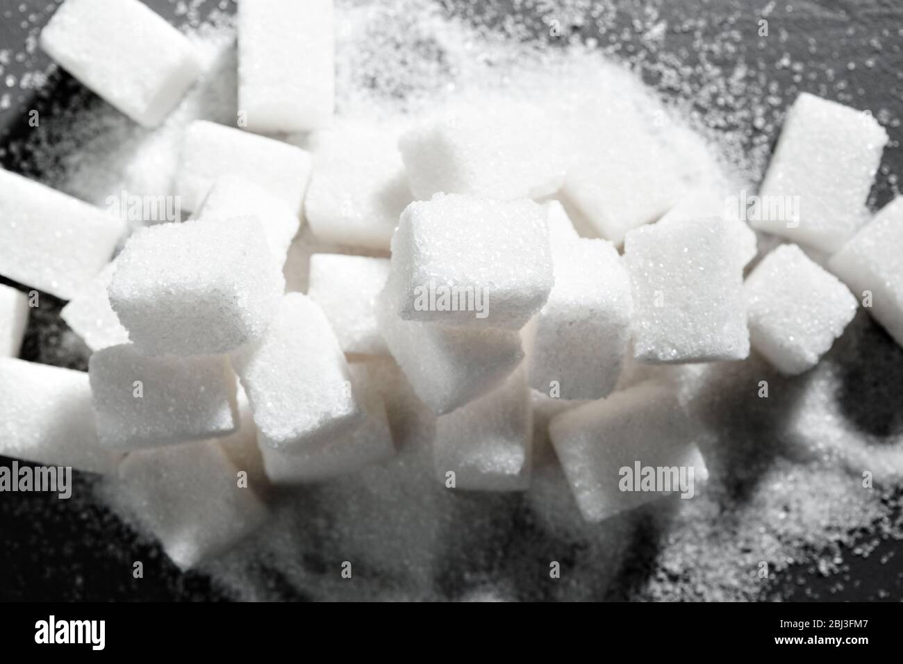 Sugar lumps piled up together against a black background Stock Photo ...