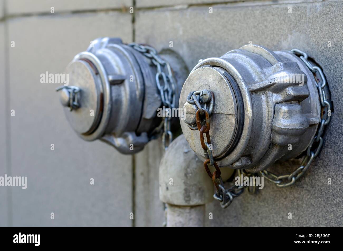 Aluminum fire hydrants in the wall with covers on chains. Two fire ...