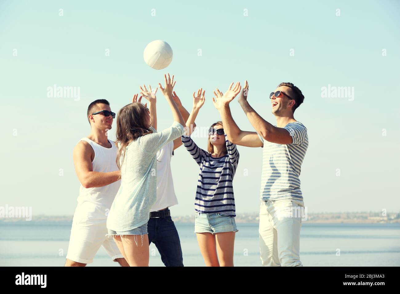 Young people playing with ball on the riverside Stock Photo - Alamy