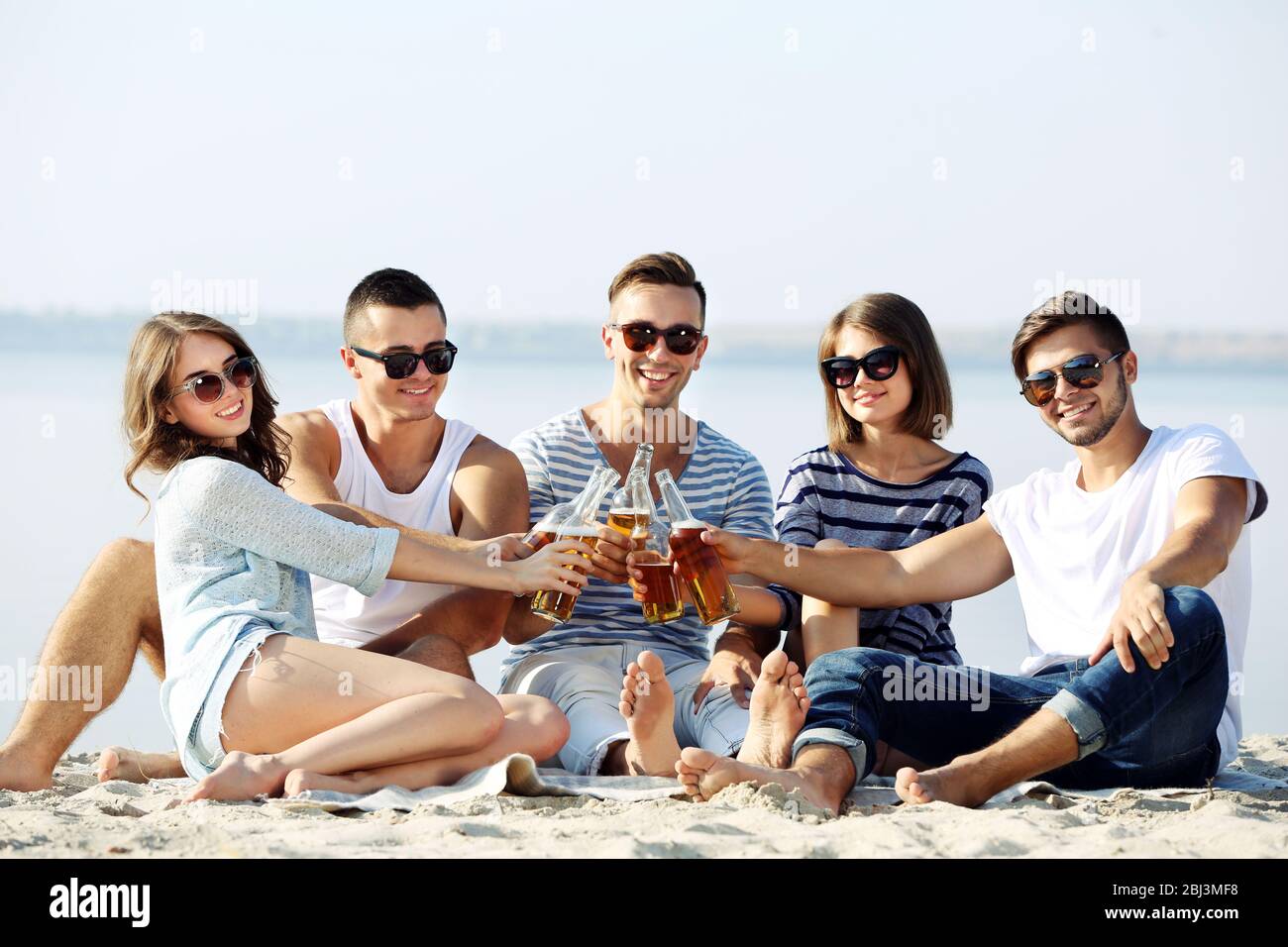 Young people with beer on the riverside Stock Photo - Alamy