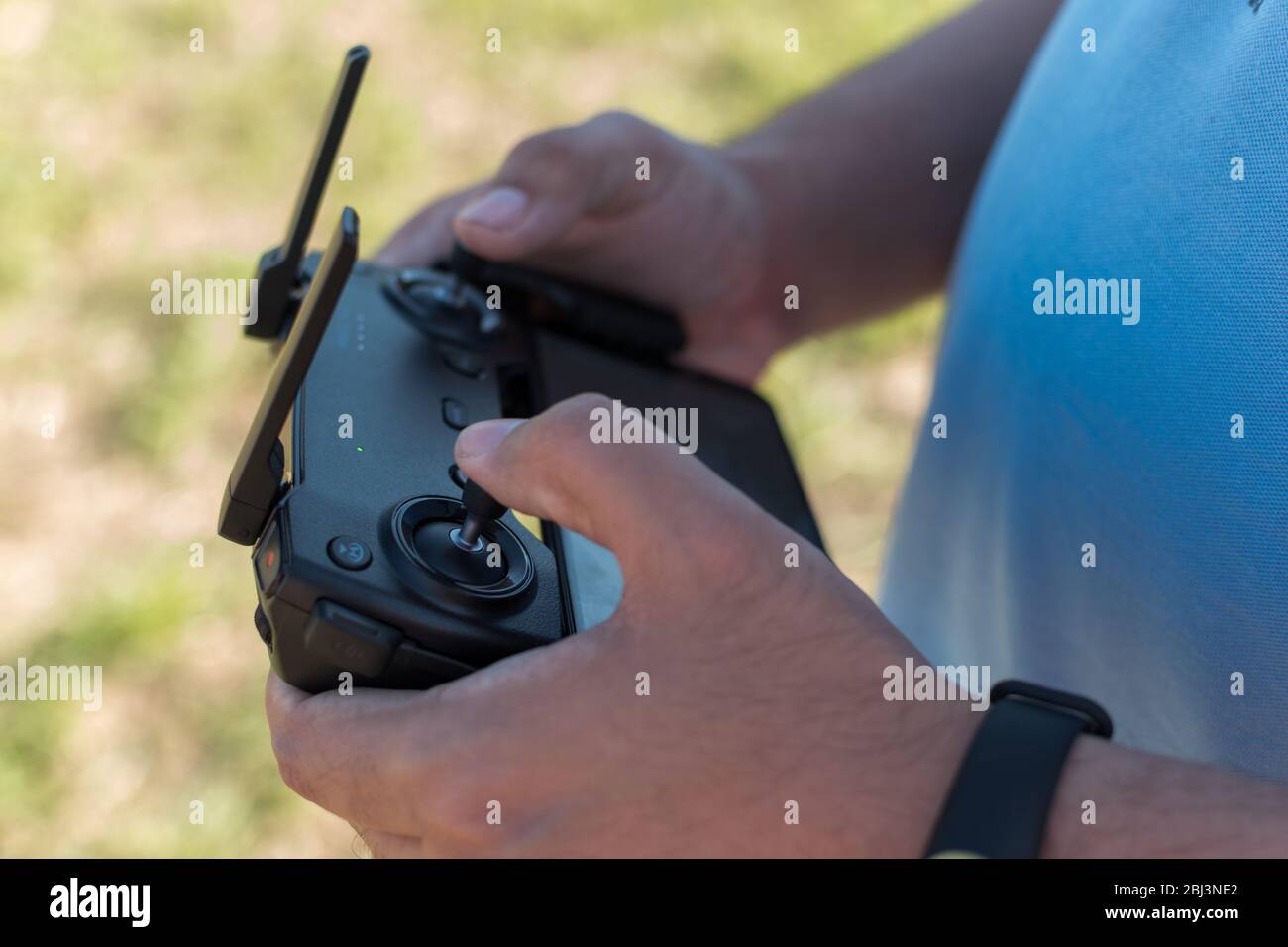 Hand holding drone remote controler to operate flying drone on a sunny ...