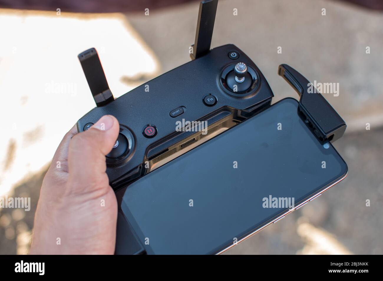 Hand holding drone remote controler to operate flying drone on a sunny ...