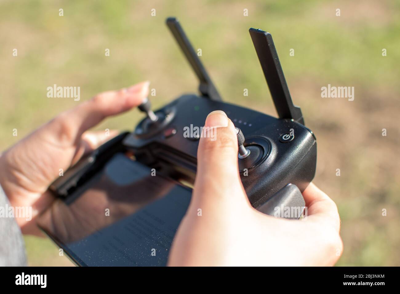 Hand holding drone remote controler to operate flying drone on a sunny ...
