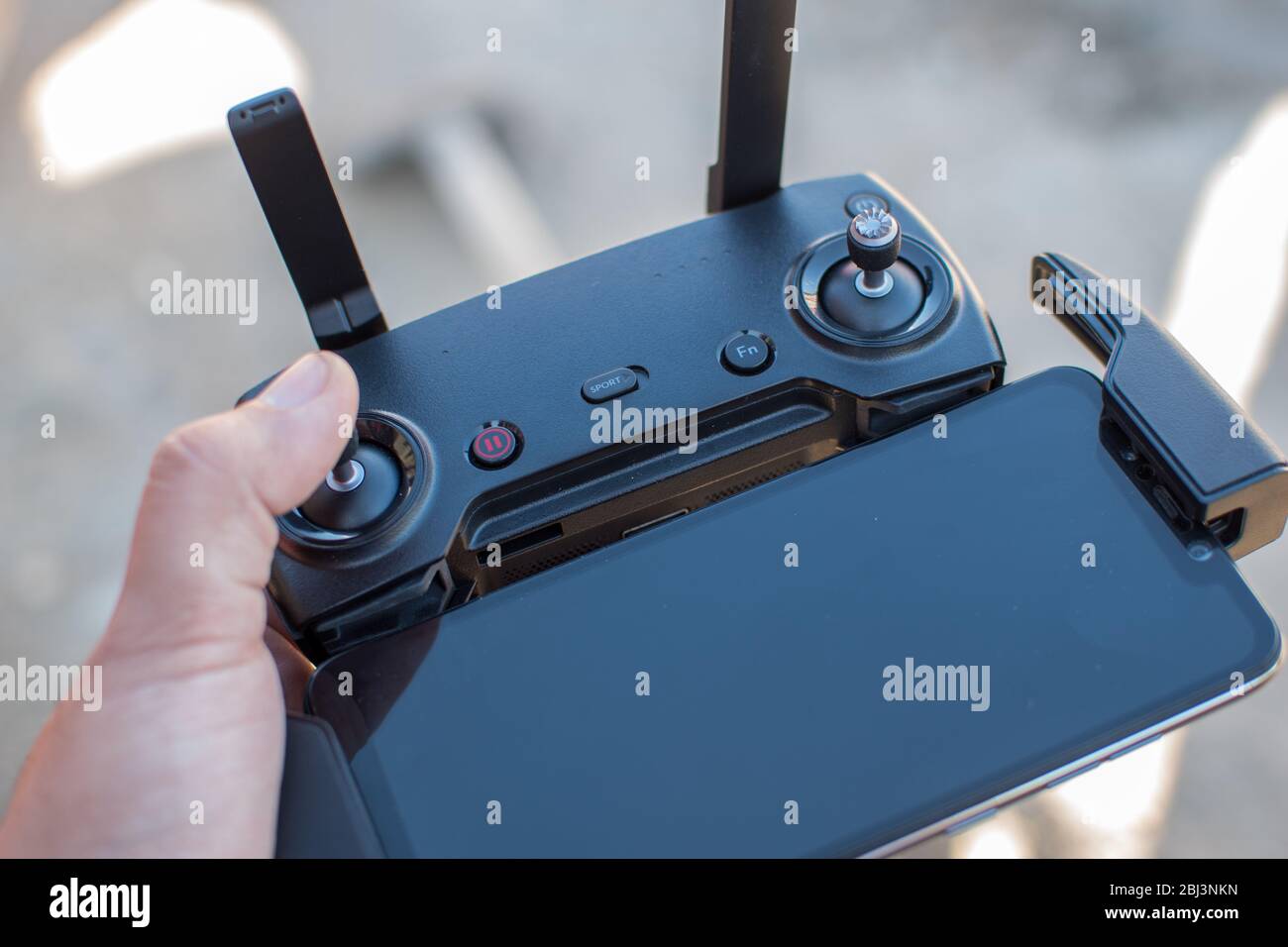 Hand holding drone remote controler to operate flying drone on a sunny ...