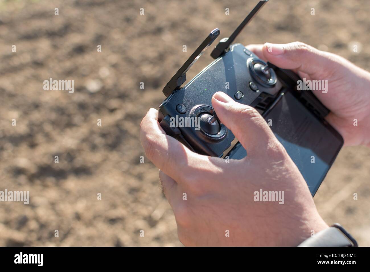 Hand holding drone remote controler to operate flying drone on a sunny ...