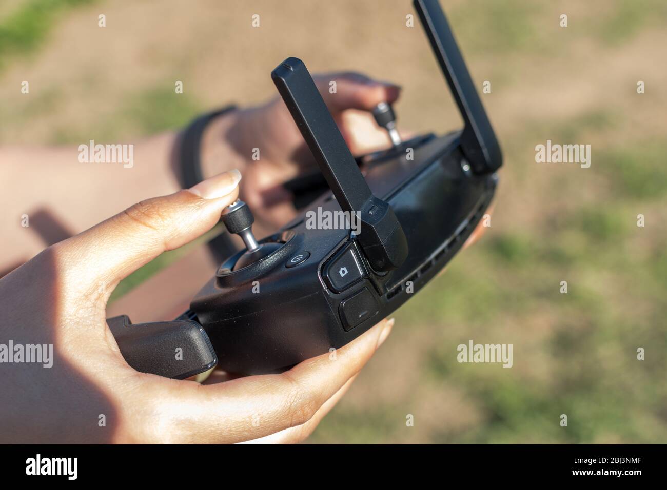 Hand holding drone remote controler to operate flying drone on a sunny ...