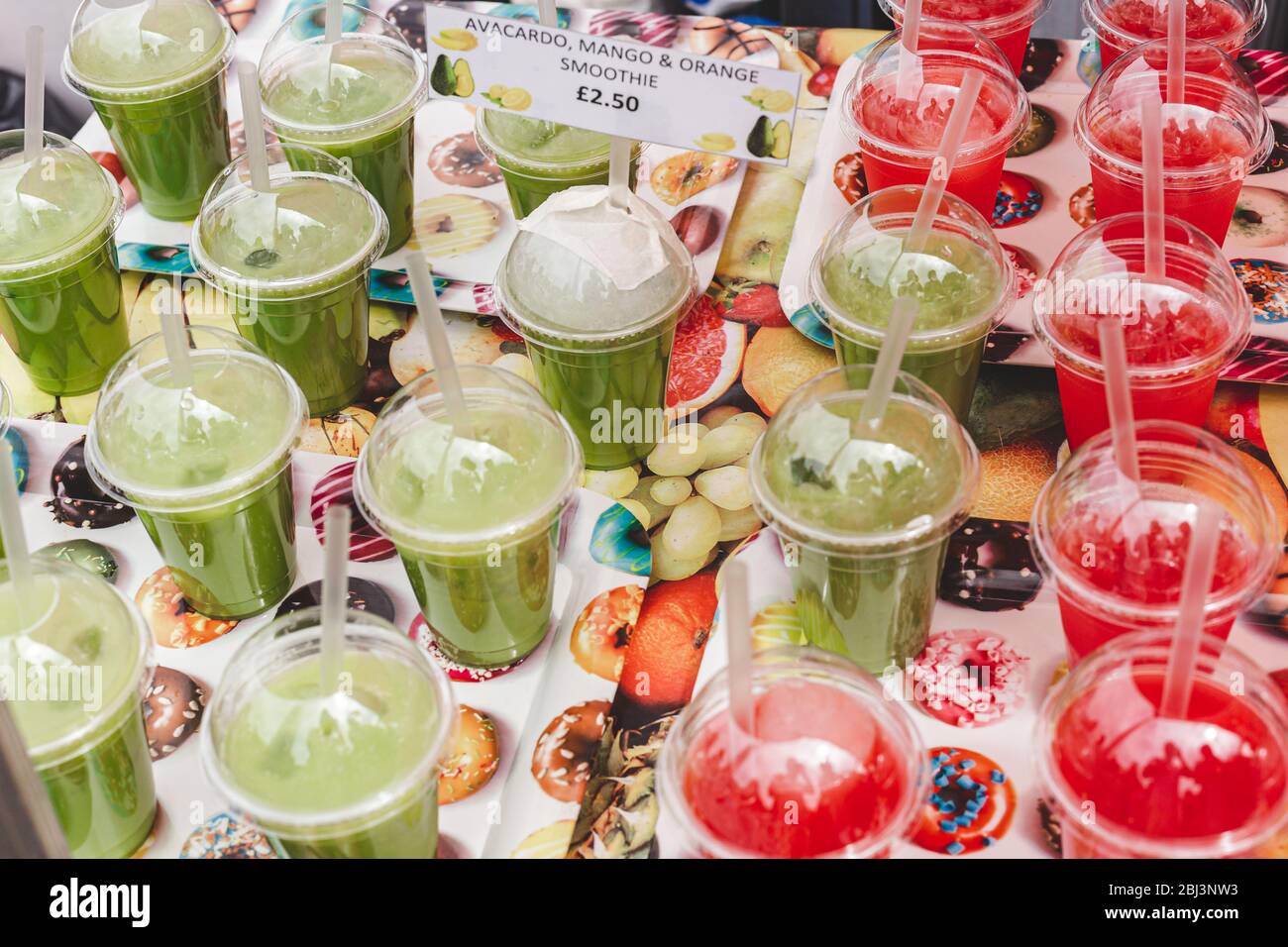 Close up of a variety of smoothies on sale in a stall in a food market ...