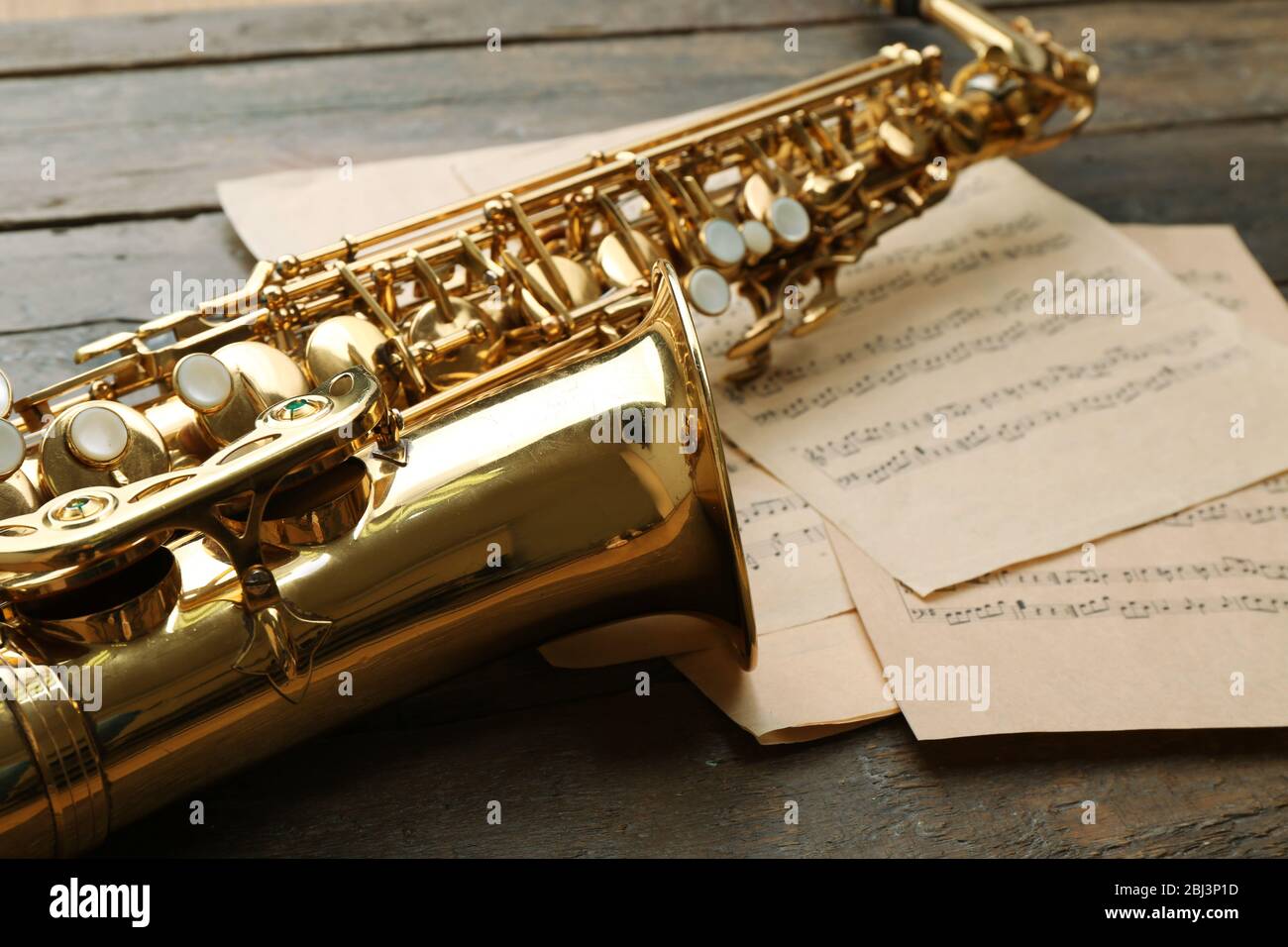 Beautiful golden saxophone with musical notes on wooden background ...