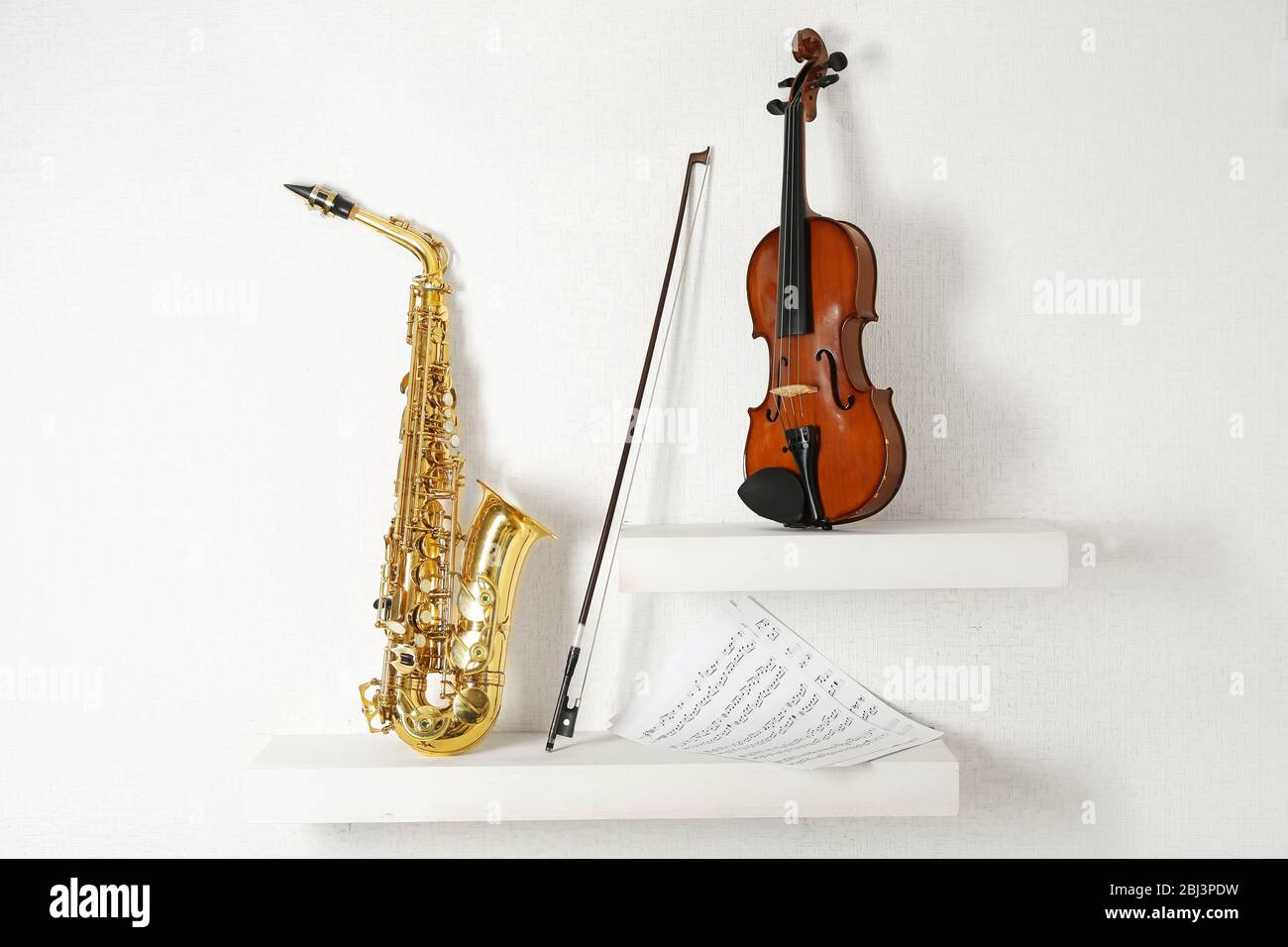 Musical instruments on decorated shelves against white wall background ...