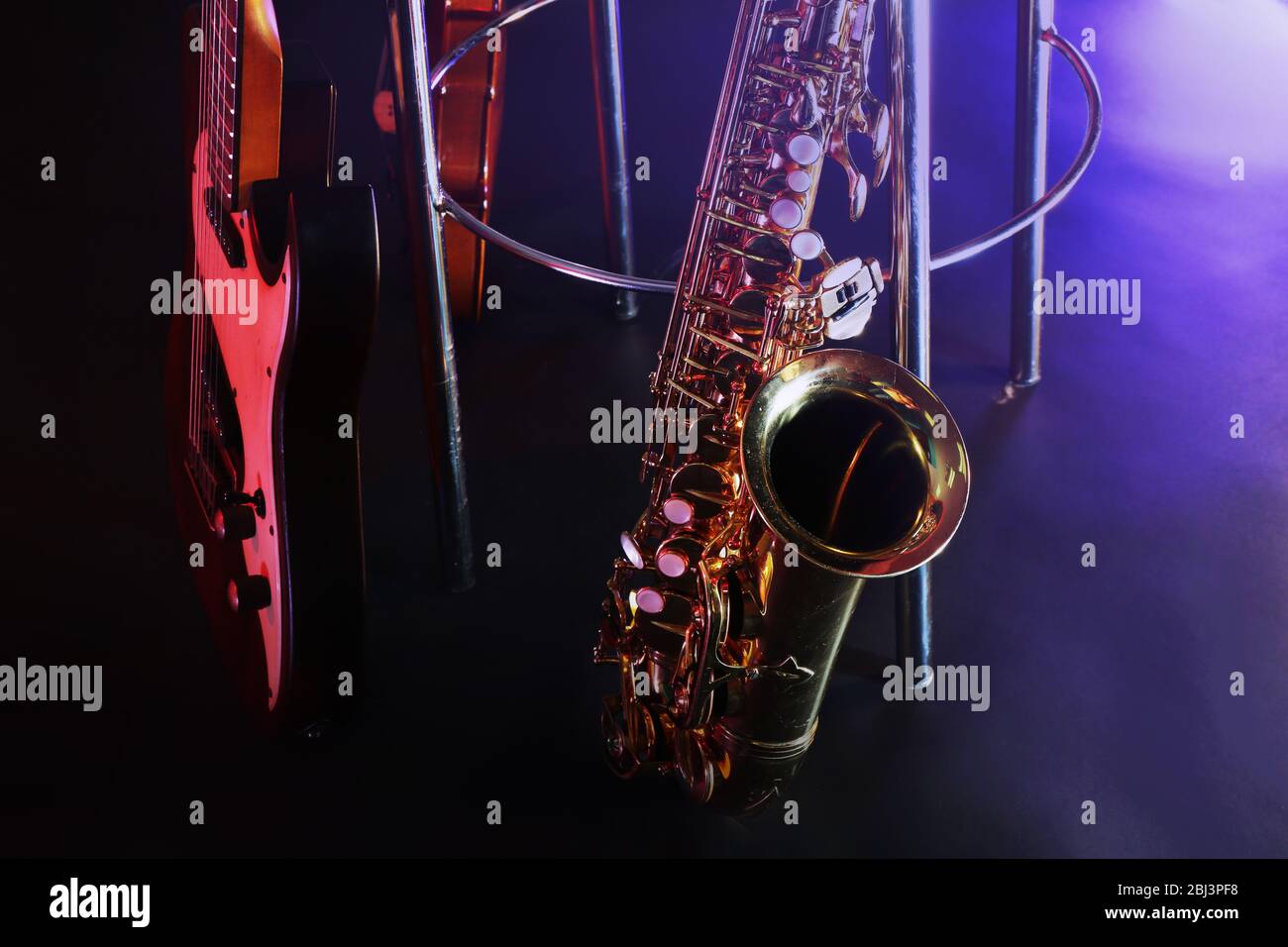Beautiful golden saxophone and guitar near bar stool on a scene Stock ...