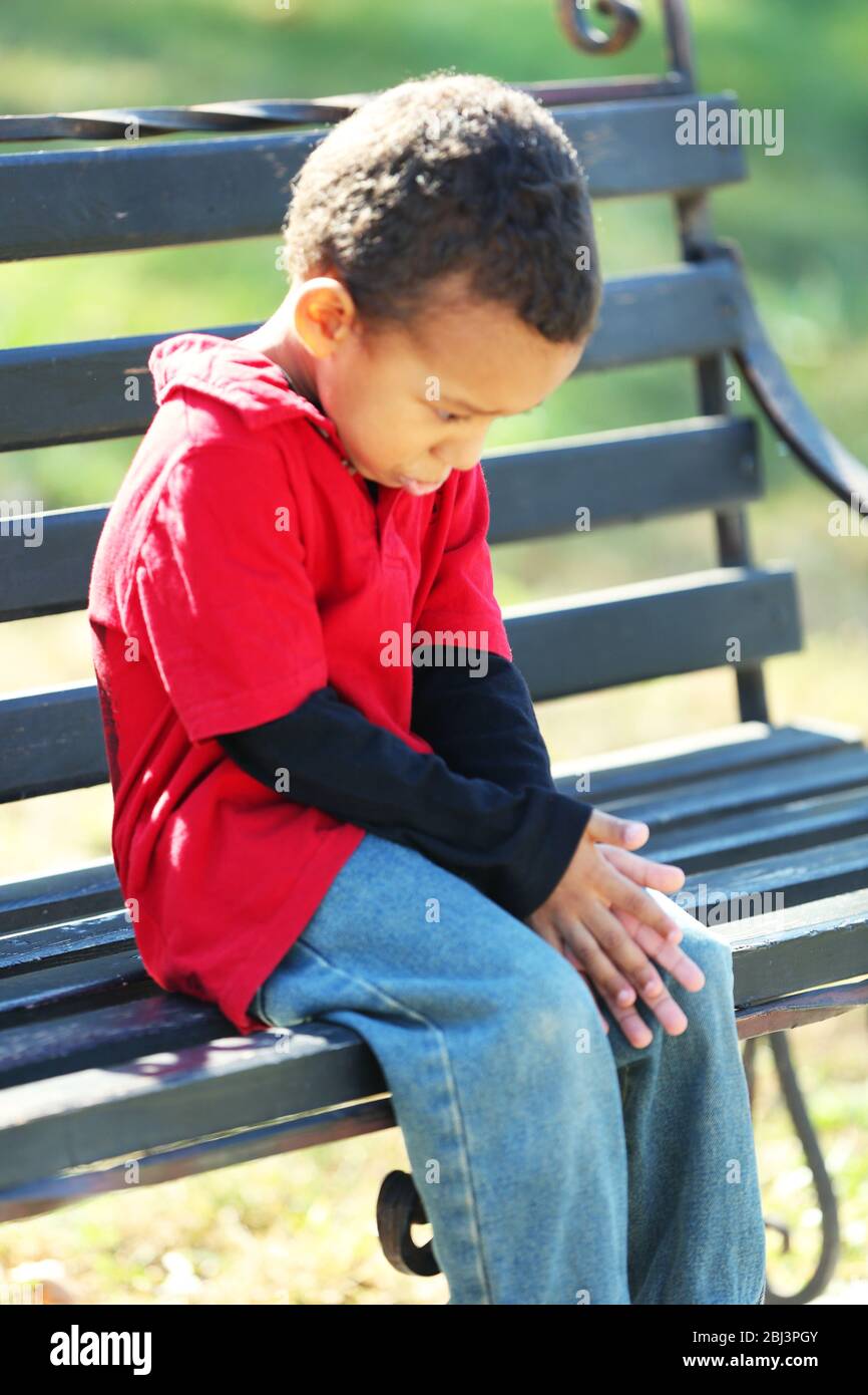 Little boy sitting on the bench in park Stock Photo - Alamy
