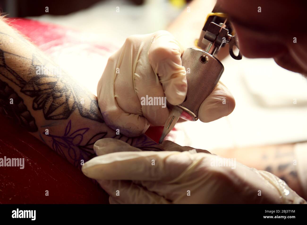 Professional tattoo artist doing tattoo on client hand Stock Photo - Alamy