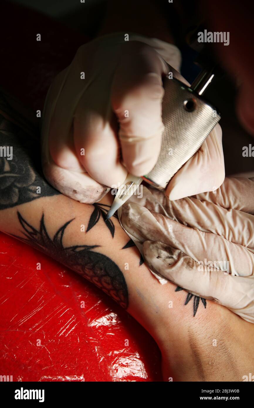Professional tattoo artist doing tattoo on client hand Stock Photo - Alamy