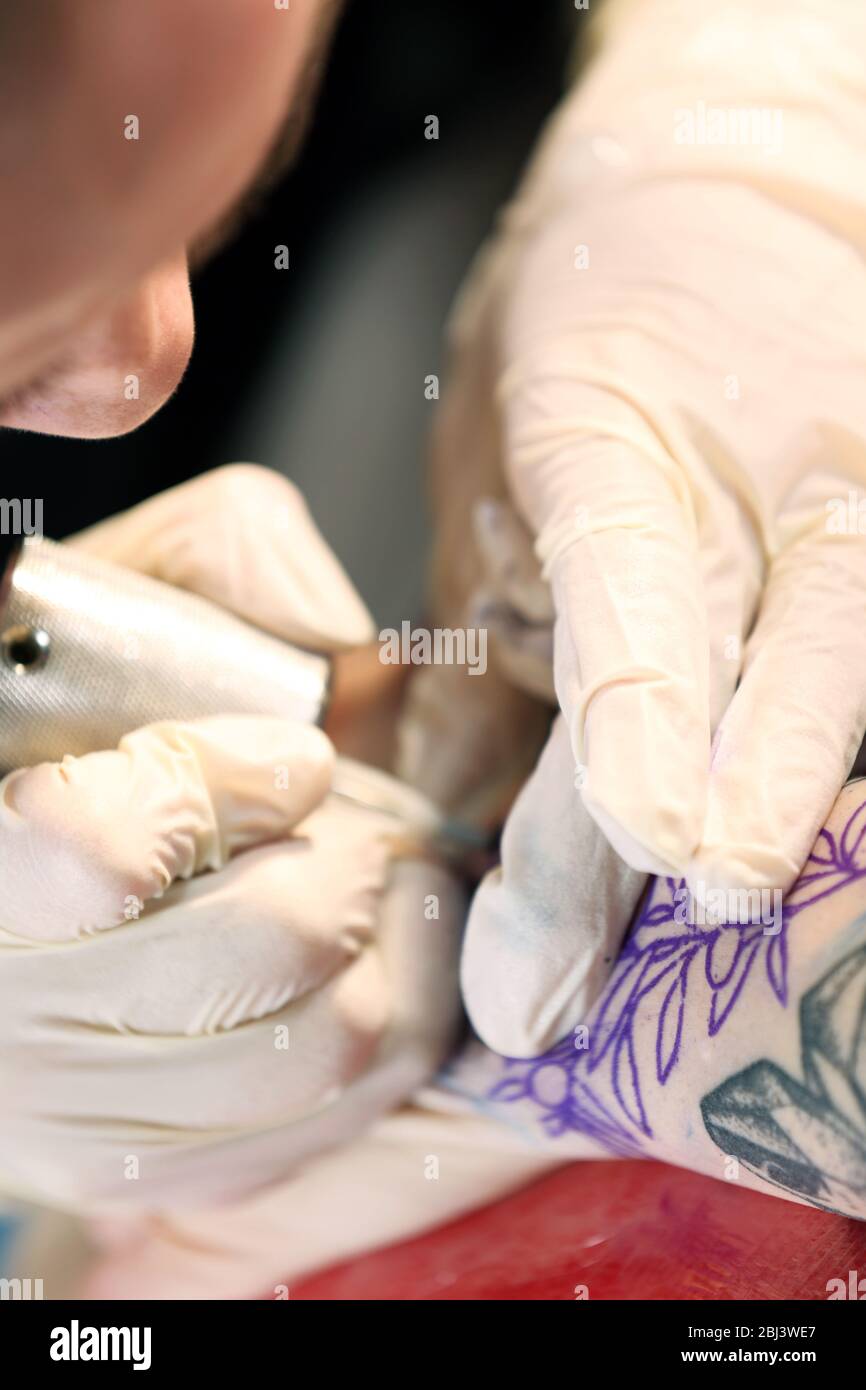 Professional tattoo artist doing tattoo on client hand Stock Photo - Alamy