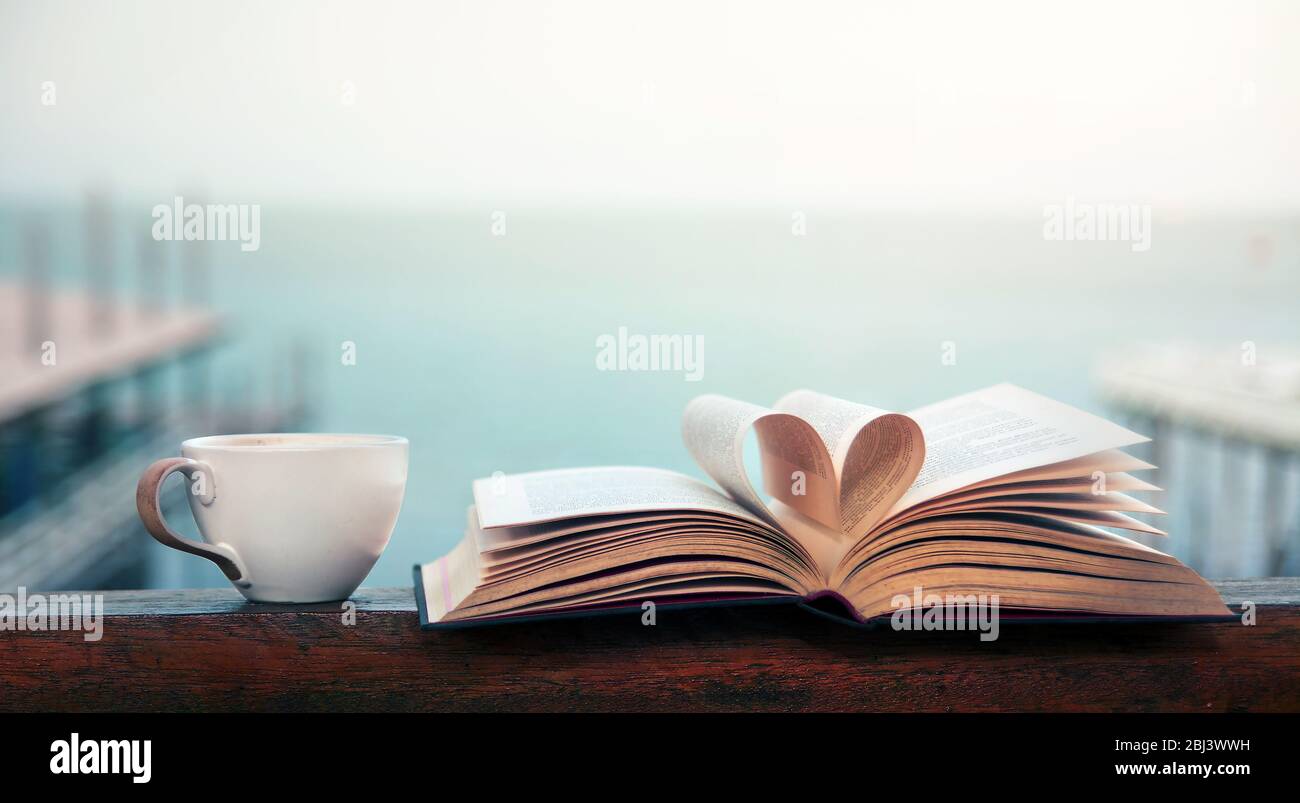 Book and coffee time on the deck by the seaside Stock Photo - Alamy