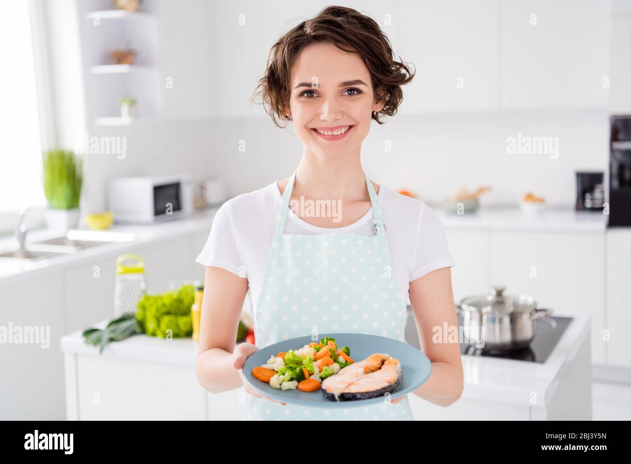 Photo of attractive housewife lady chef showing grilled salmon trout ...