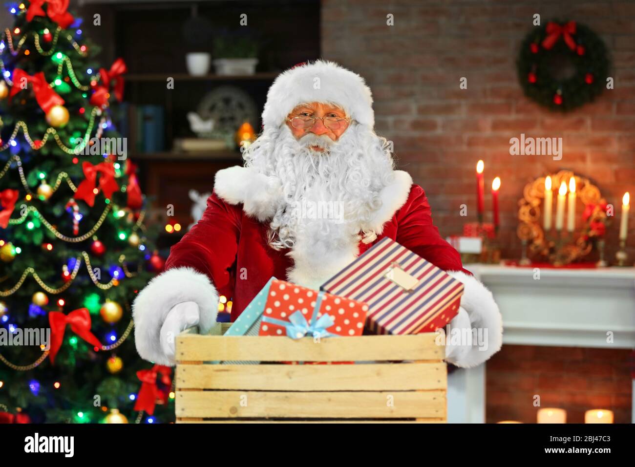 Santa holding gift on Christmas tree background Stock Photo - Alamy