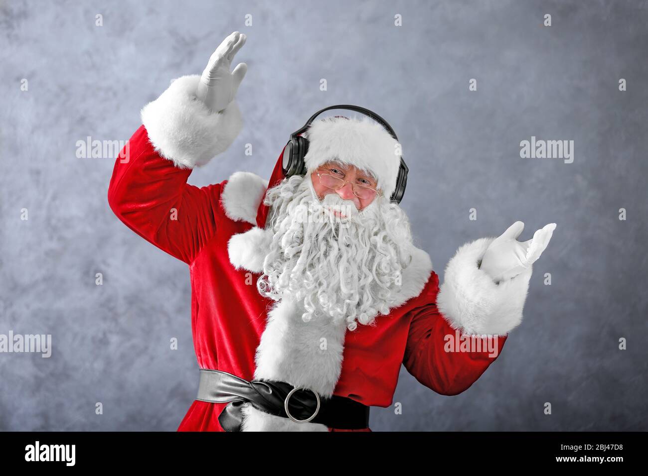 Santa Claus with headphones listening to music on gray wall background ...
