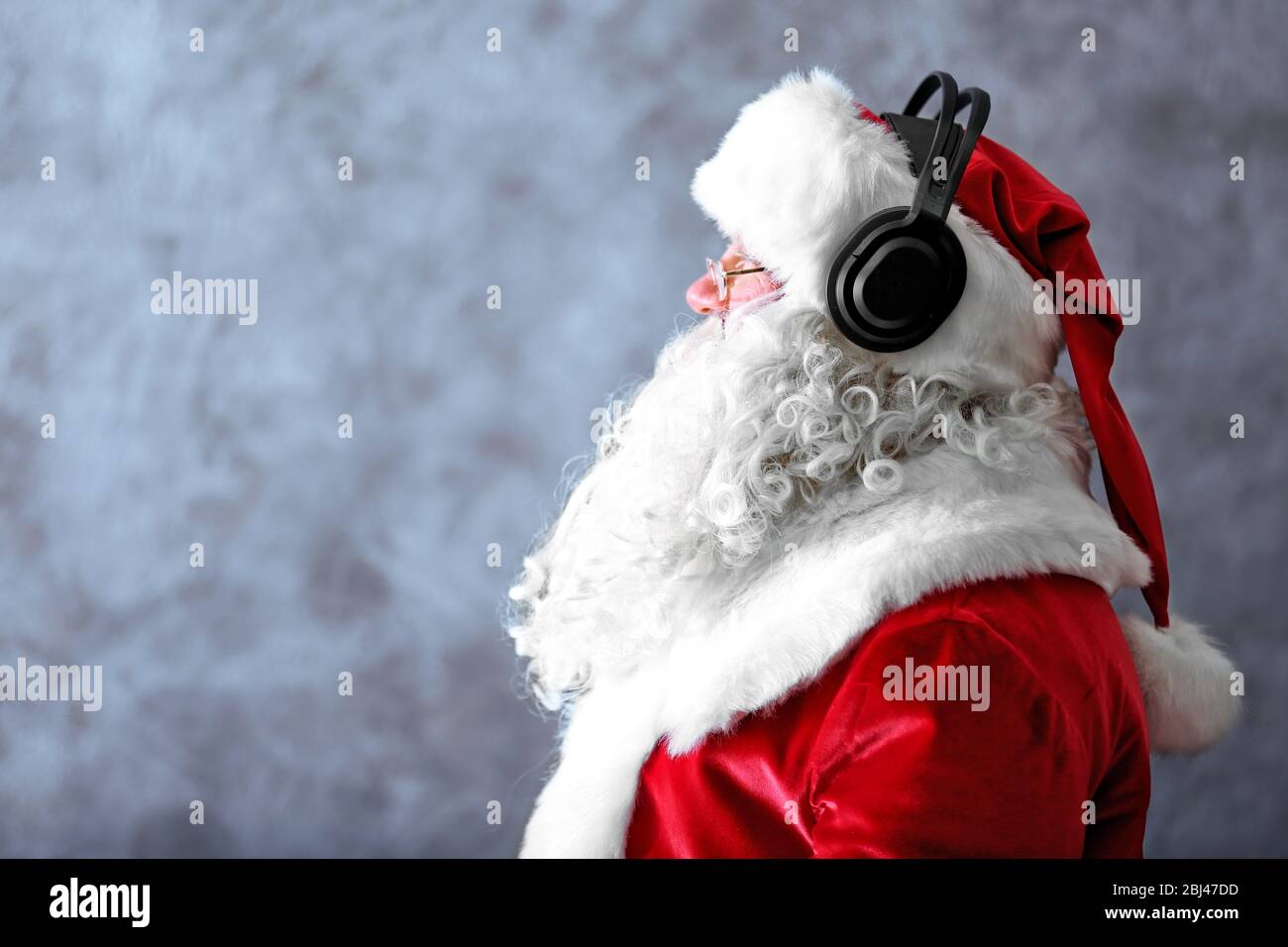 Santa Claus with headphones listening to music on gray wall background ...