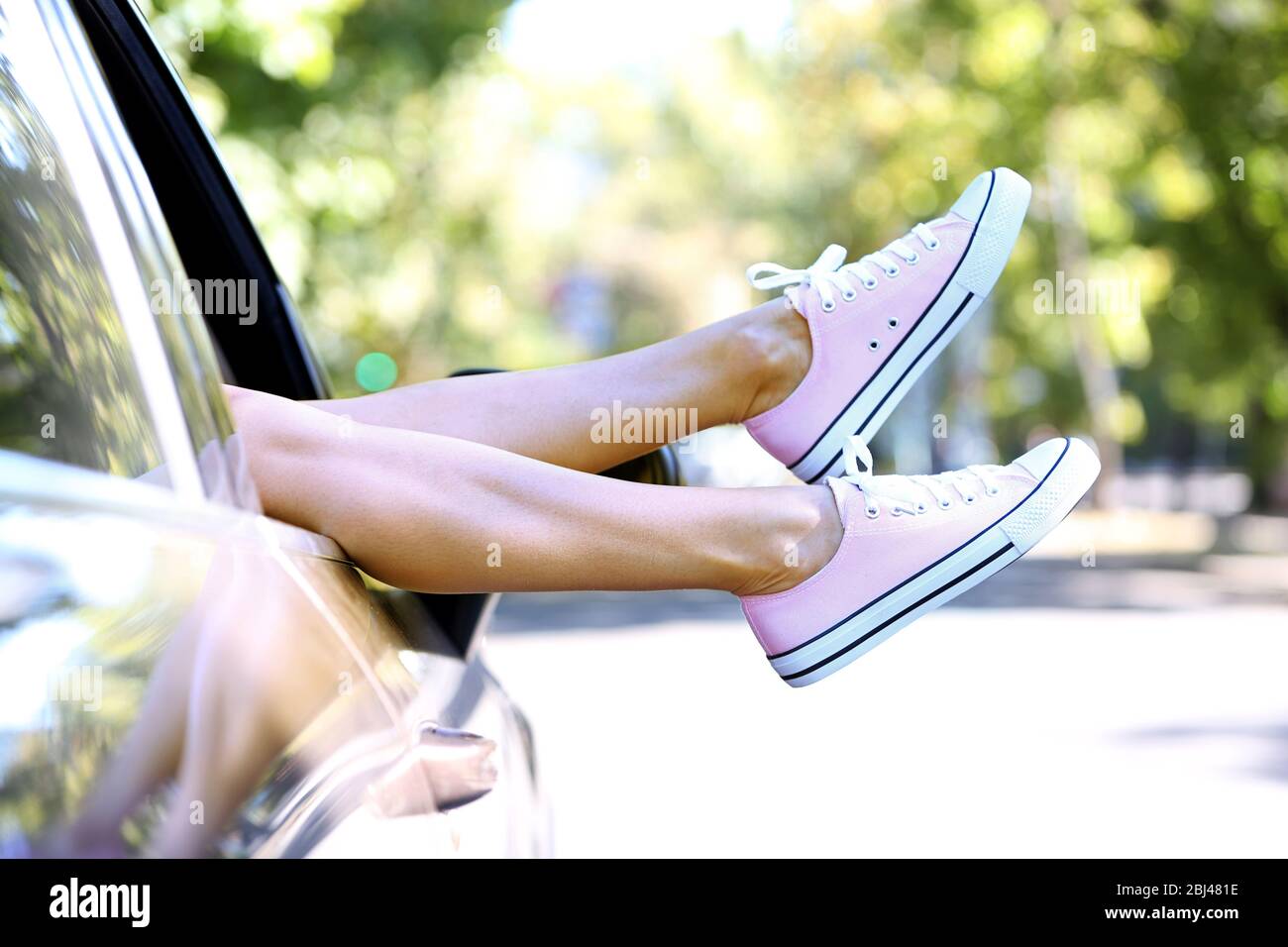 Woman's legs out of the car window Stock Photo - Alamy