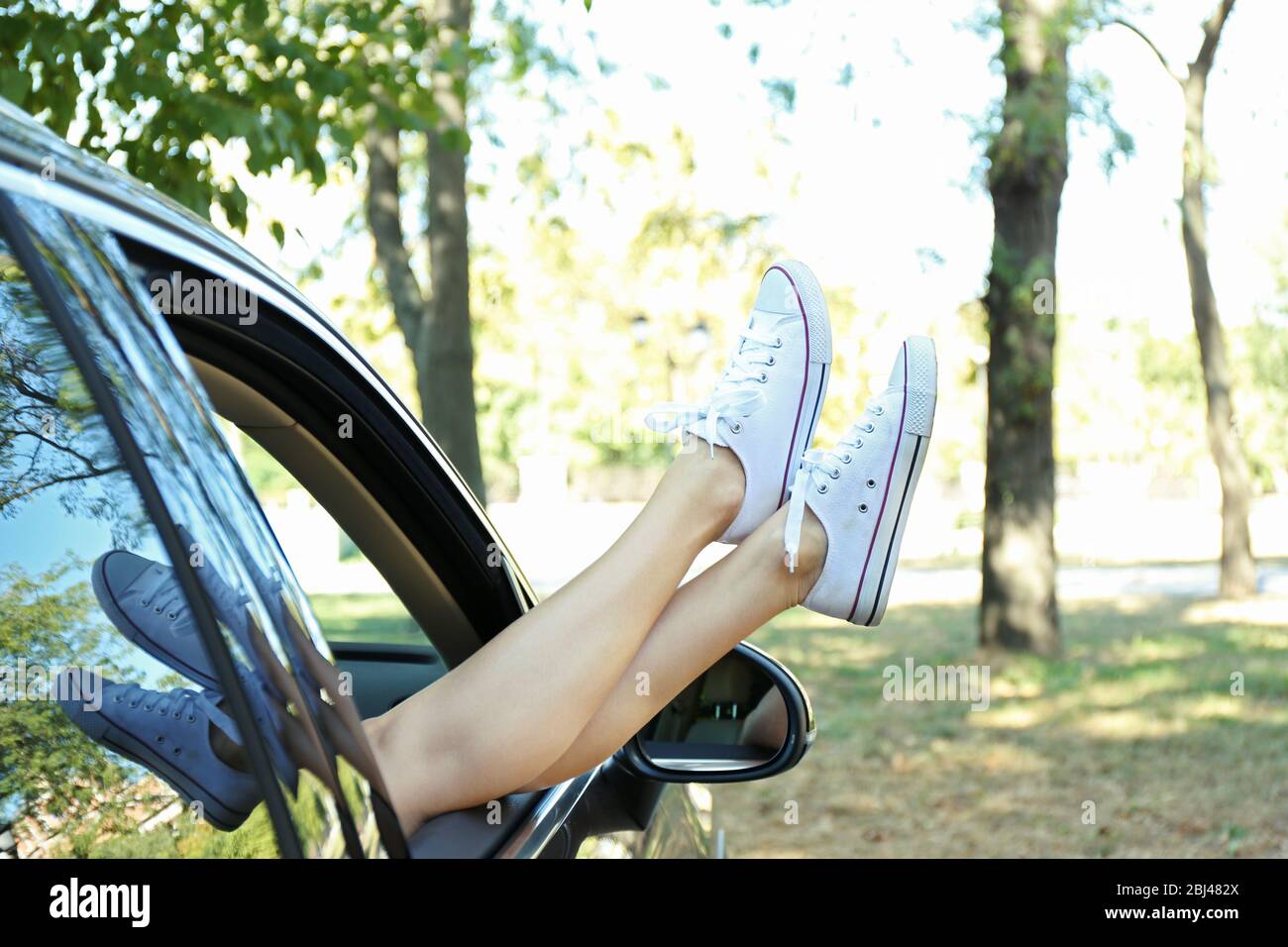 Woman's legs out of the car window Stock Photo - Alamy
