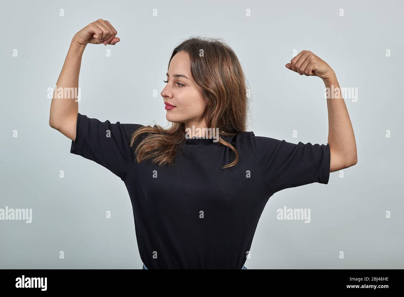 woman on gray background, strong girl shows muscles, bent arm at the ...