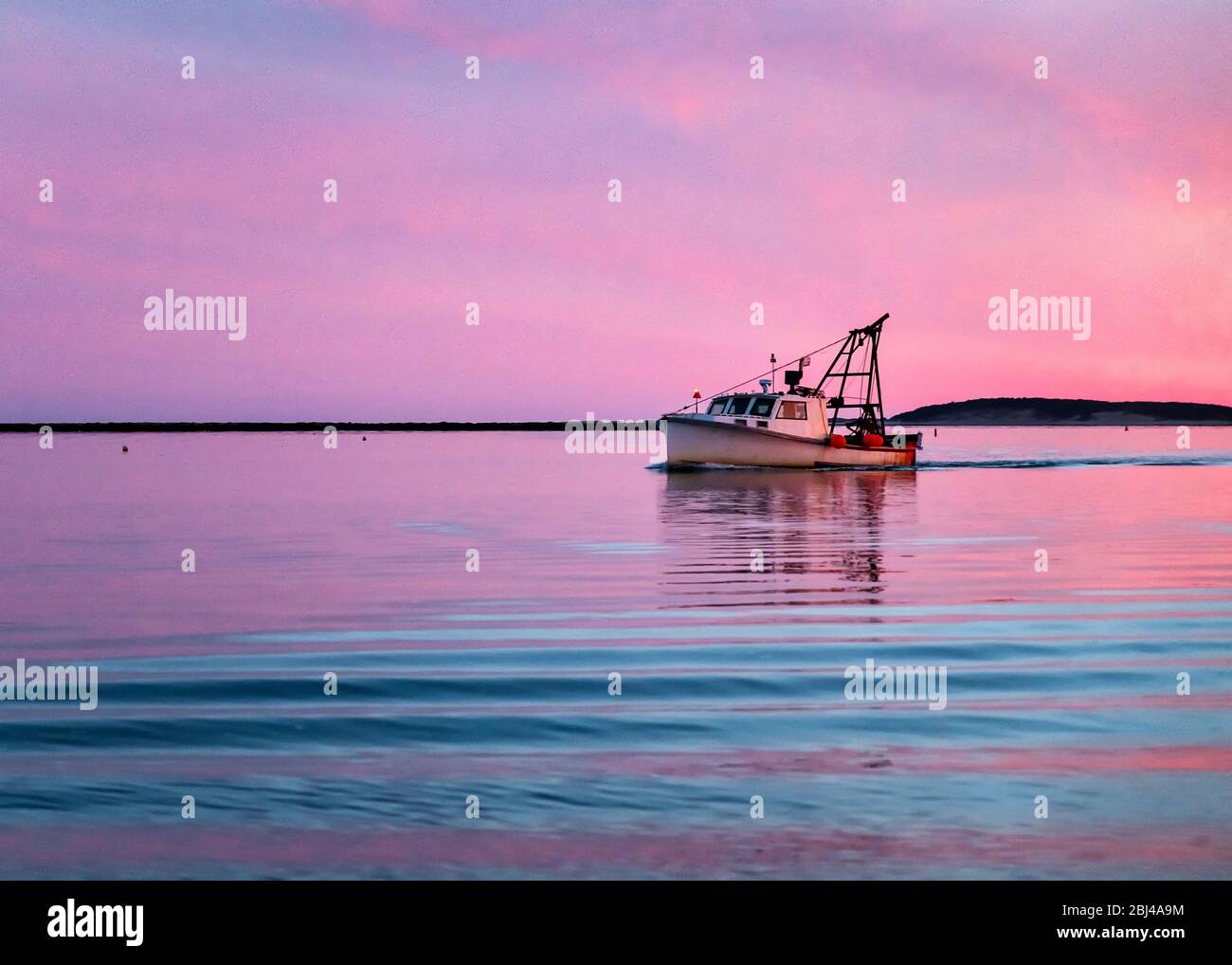 Commercial fishing boat returns to harbor at sunset at Wellfleet in ...