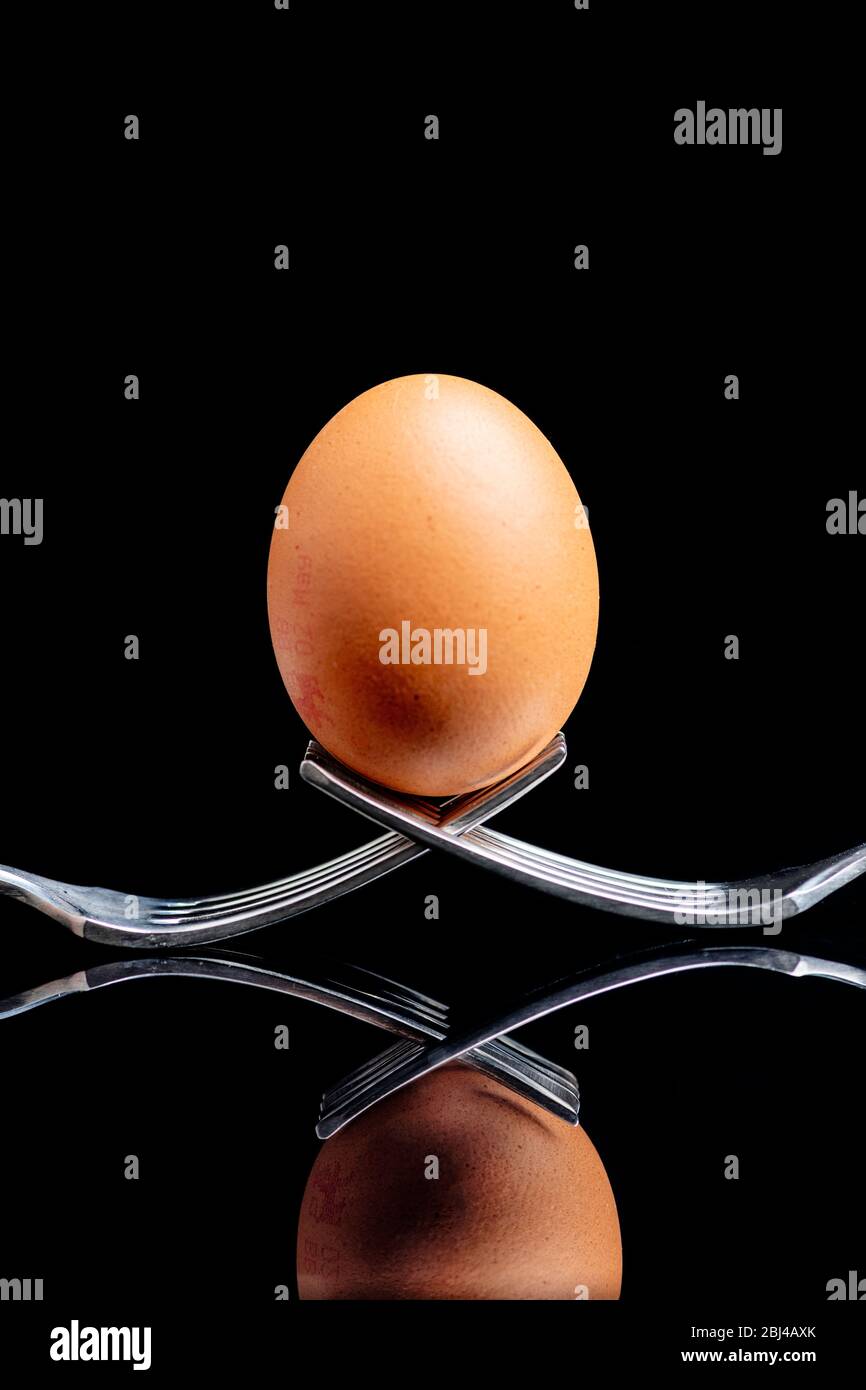 Egg balancing on two forks, balanced diet concept Stock Photo - Alamy