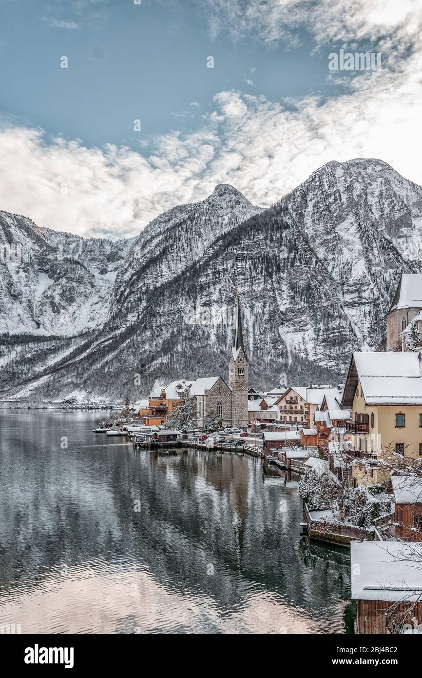 Snowy village Hallstatt by lake at foot of snow mountain with clear sky ...