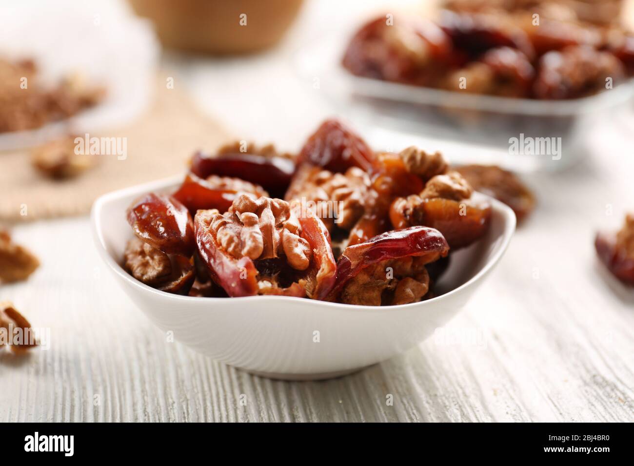 Walnut and date fruit in plate on wooden table, close-up Stock Photo ...
