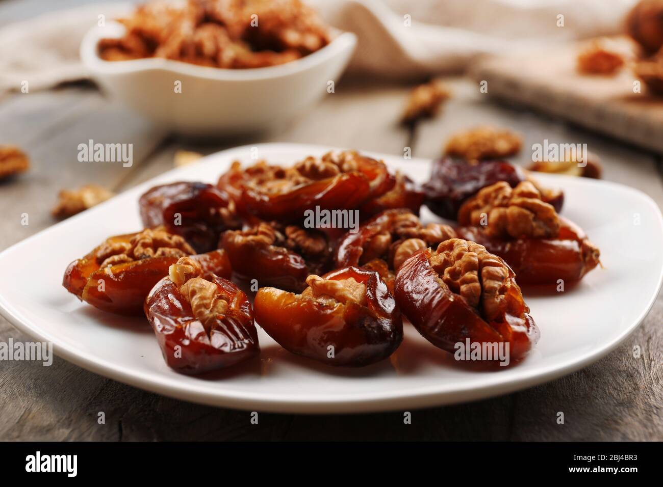 Walnut and date fruit in plate on wooden table, close-up Stock Photo ...