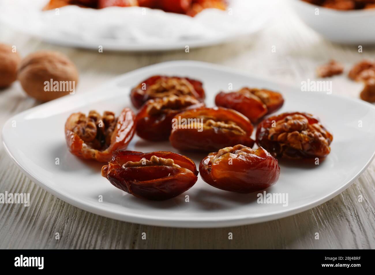Walnut and date fruit in plate on wooden table, close-up Stock Photo ...