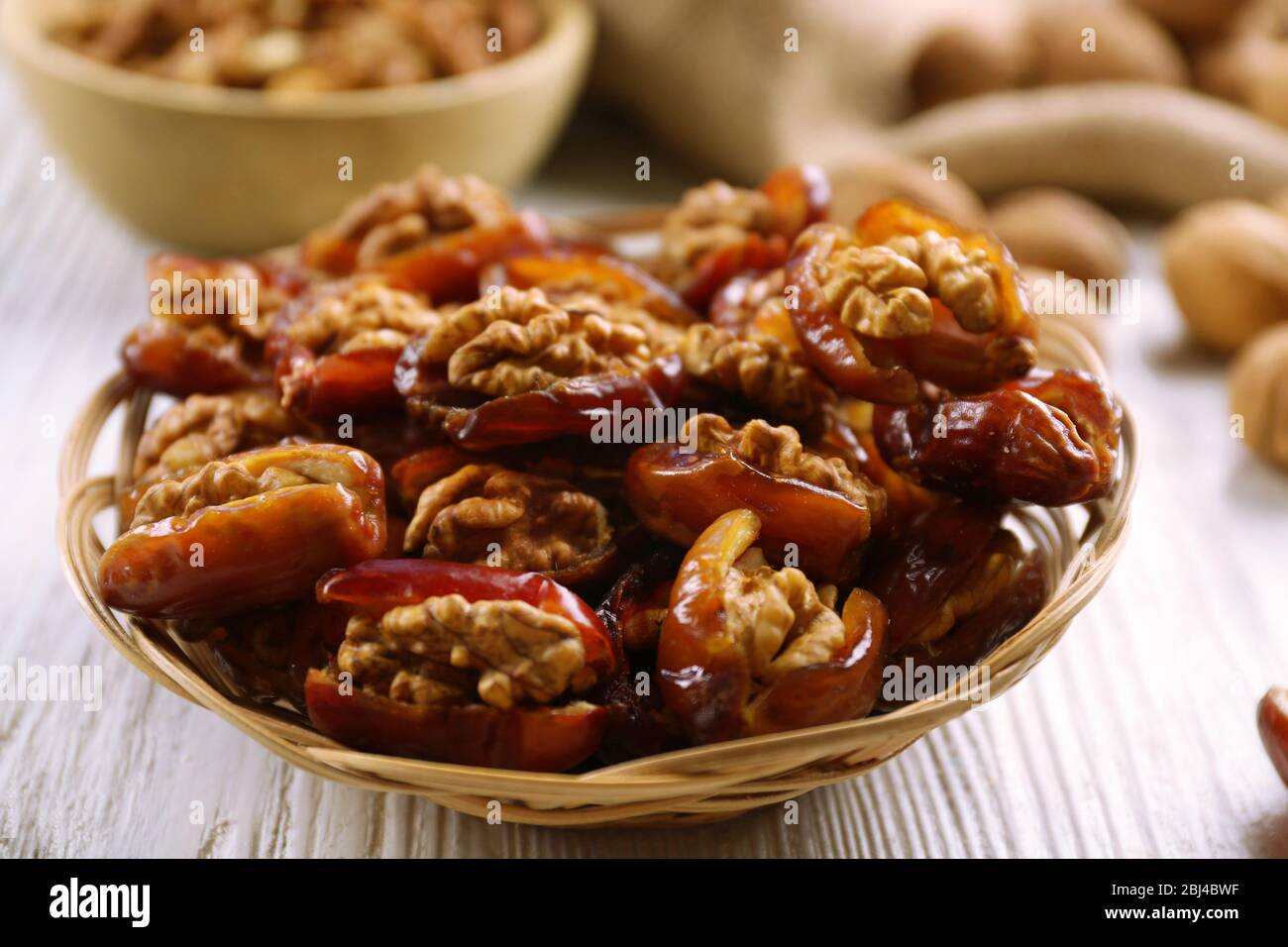 Walnut and date fruit in plate on wooden table, close-up Stock Photo ...