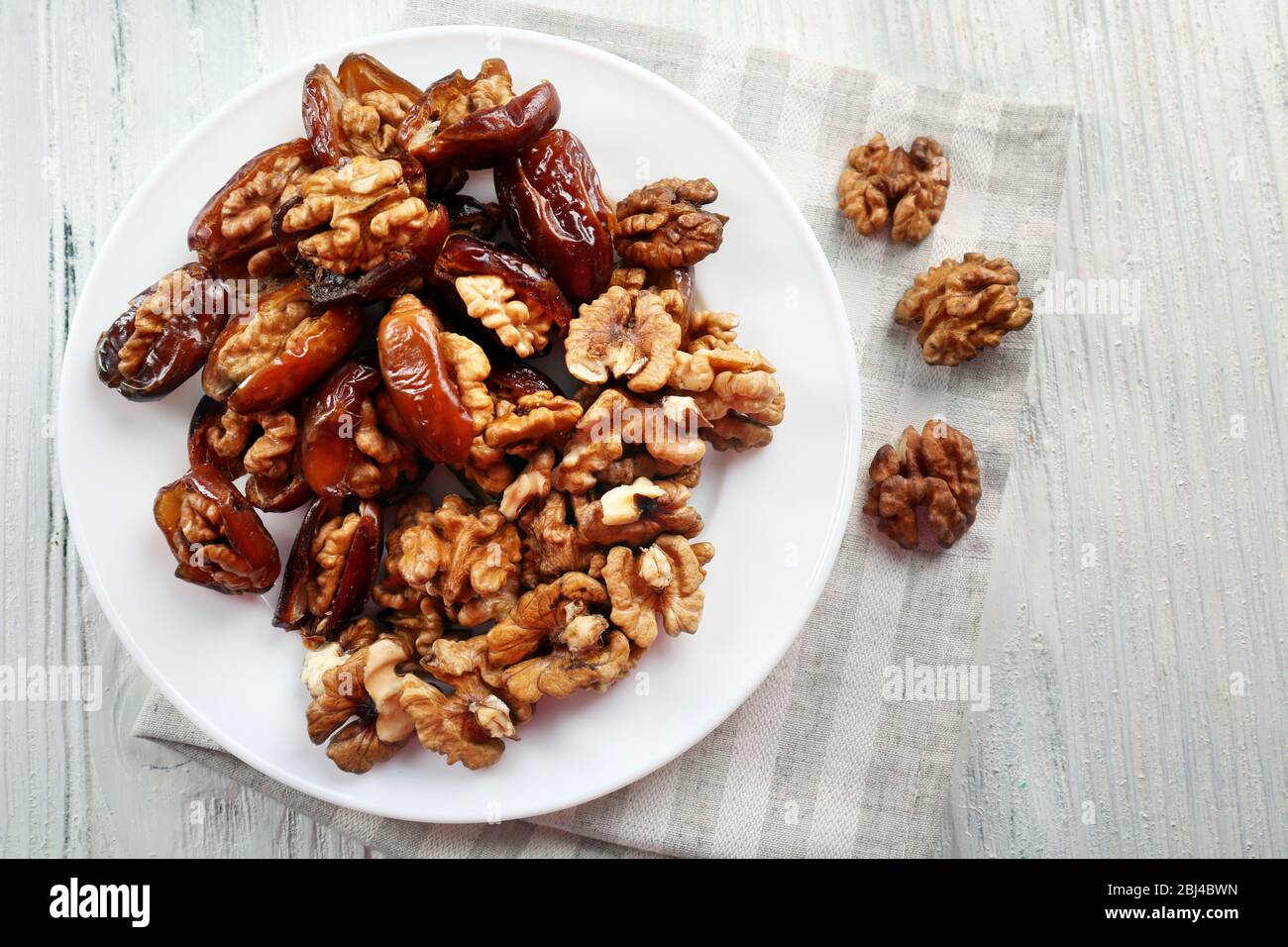 Walnut and date fruit in plate on wooden table, close-up Stock Photo ...