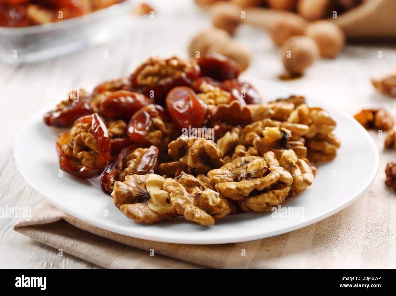 Walnut and date fruit in plate on wooden table, close-up Stock Photo ...