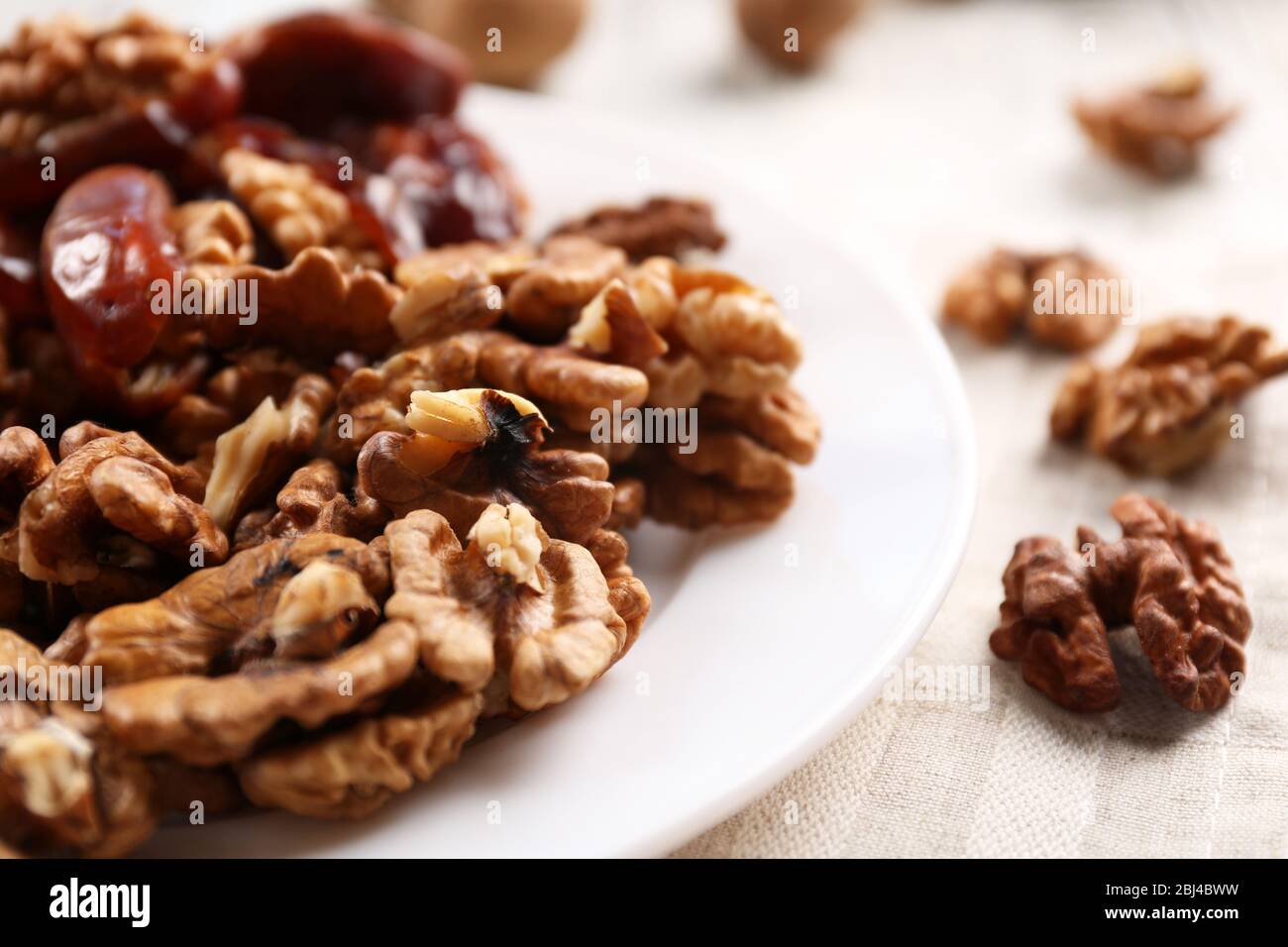 Walnut and date fruit in plate on wooden table, close-up Stock Photo ...